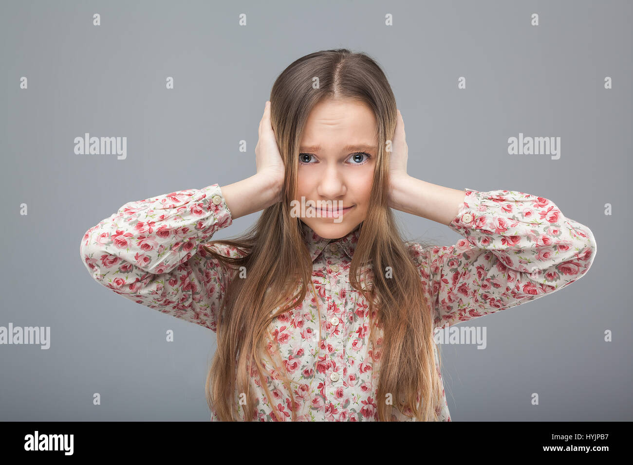 To loud. Young pretty woman in flower dress closes her ears with hands ...