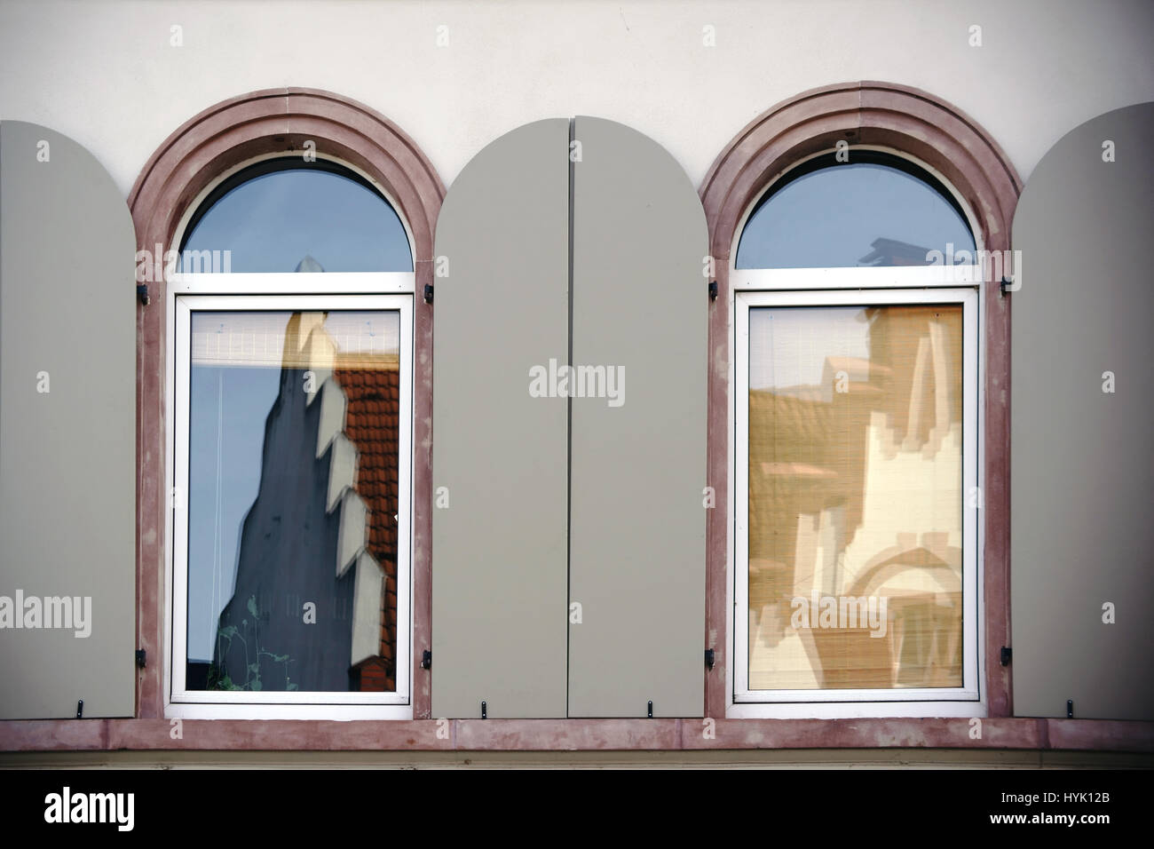 Two round-arch windows with open window shutters and reflections in the ...