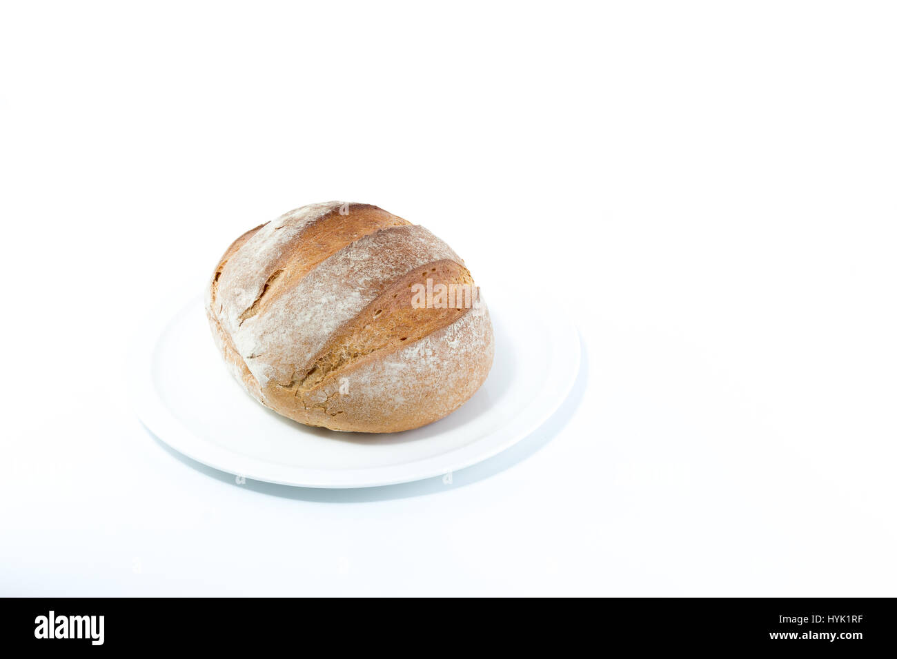 Full rustic loaf of bread on a white dish isolated on white background ...