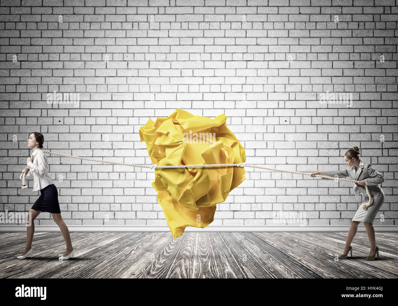 Two women pulling with effort big crumpled ball of paper as creativity ...