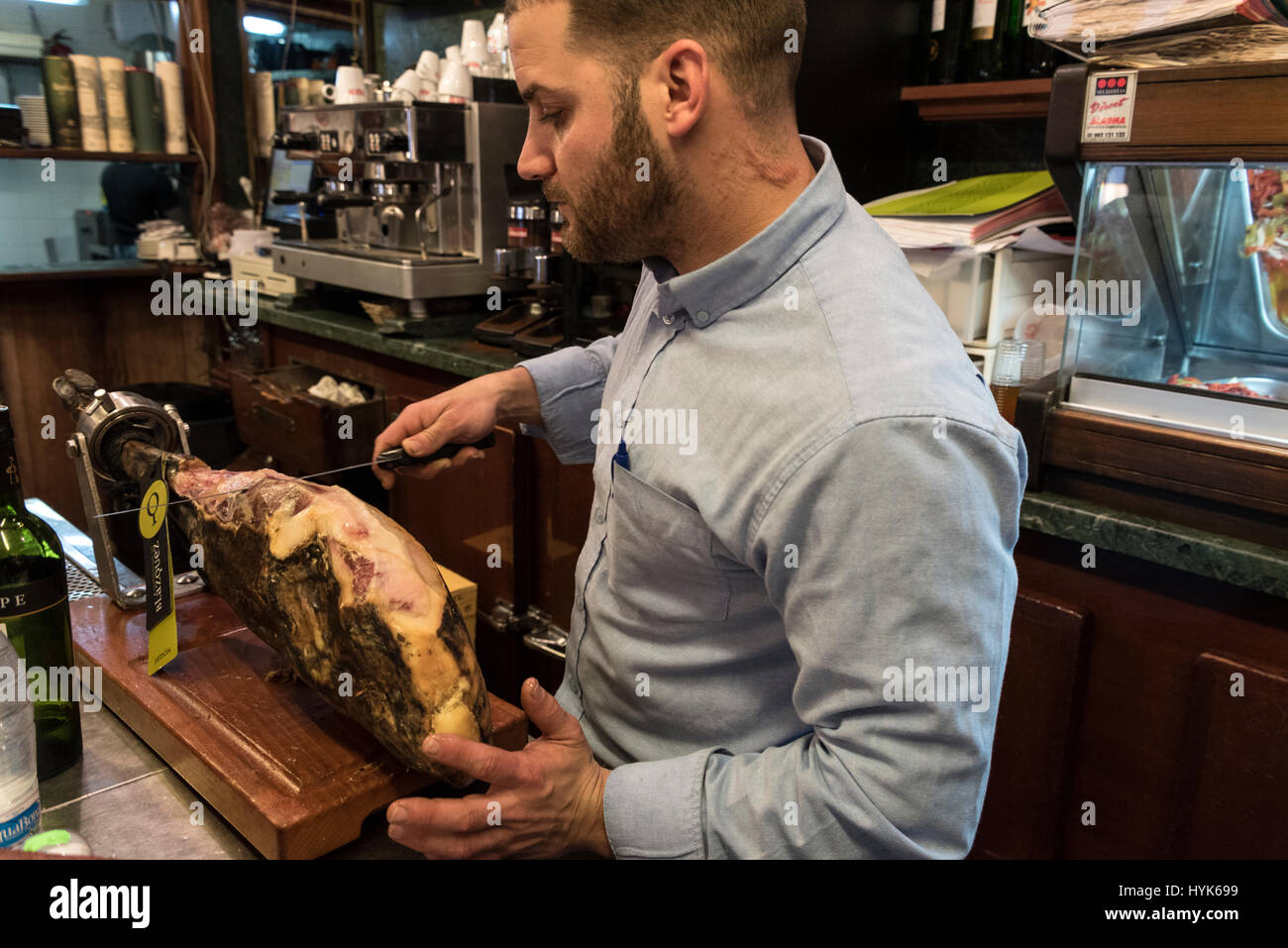A member of the bar staff carving slices of cured mountain air-dried ...