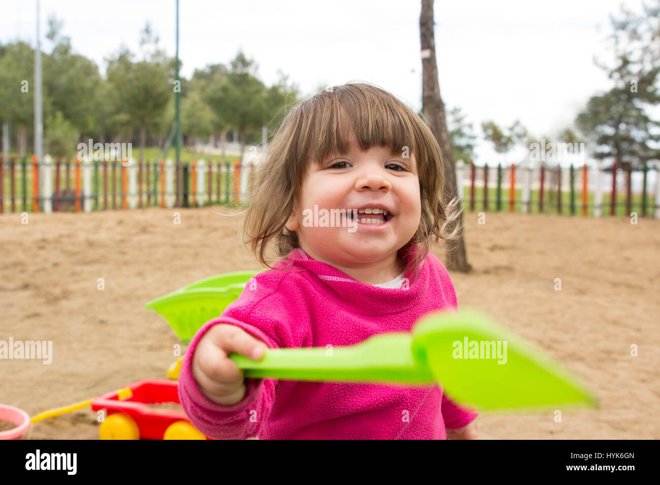 smiling little girl playing with sand giving a spade to camera Stock ...