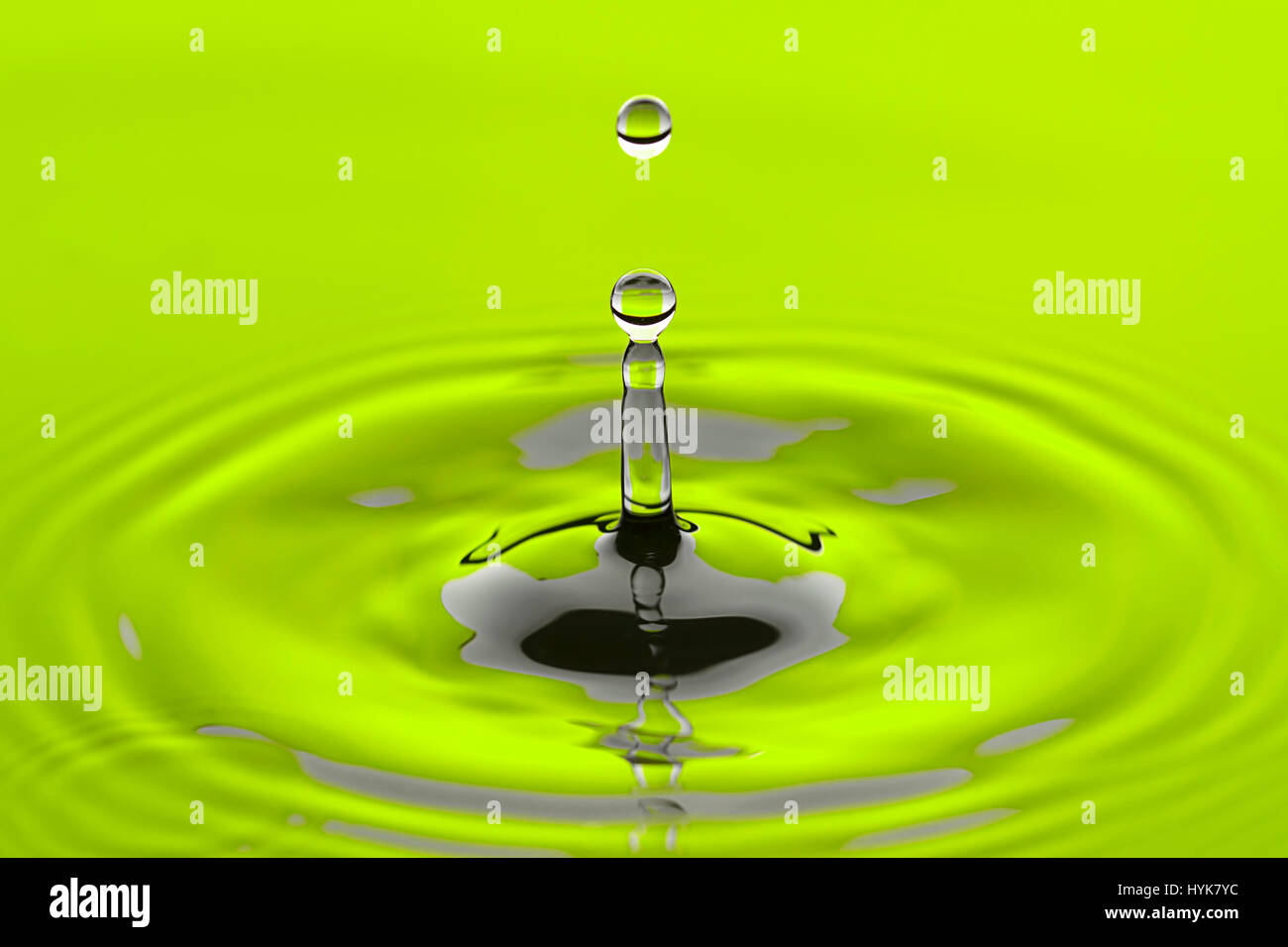 A water drop into a pool of water with green reflected into it Stock ...