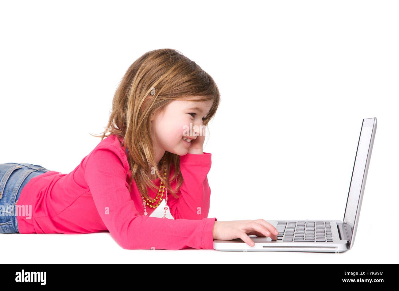 Horizontal portrait of a smiling young girl typing on laptop against ...