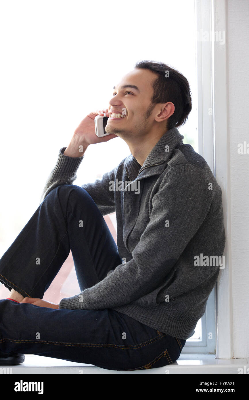 Portrait of a young man relaxing and on mobile phone at home Stock ...