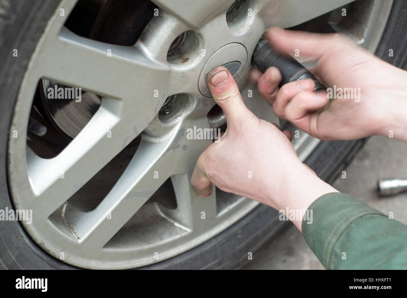 Hand of mechanic removing a car wheel nut, closeup with blurred motion ...