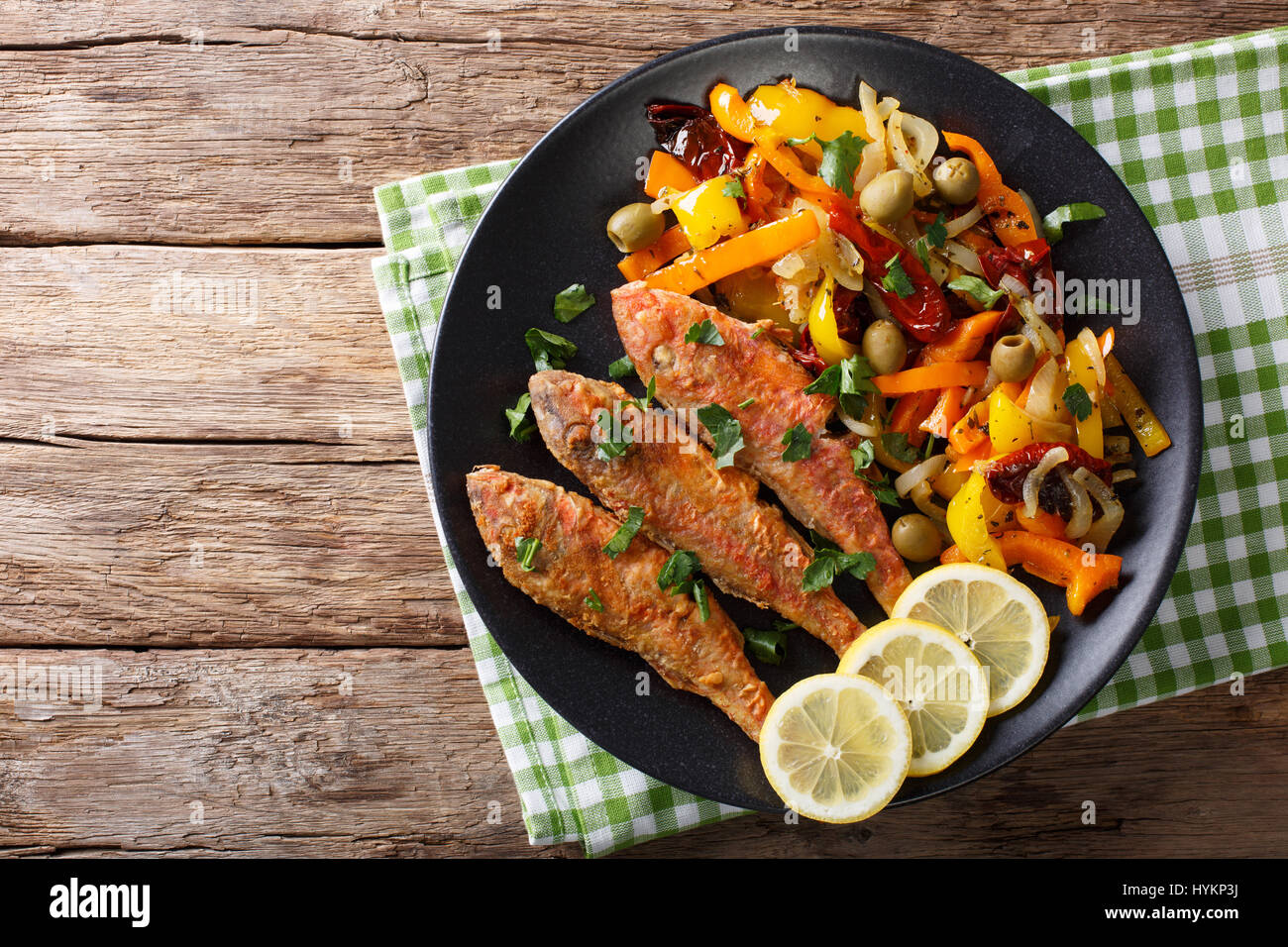 Roasted red mullet with stewed vegetables, lemon and greens close-up on ...