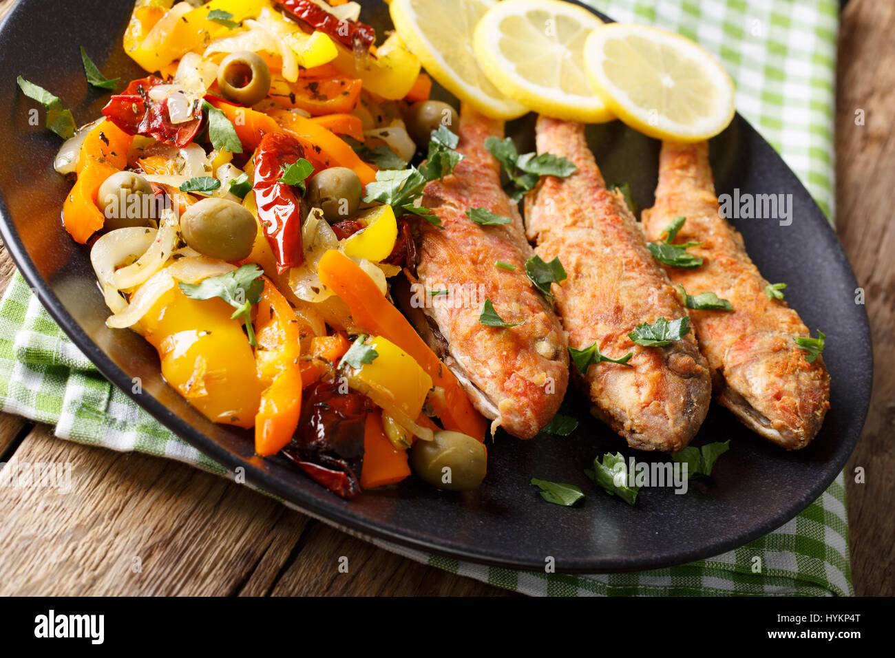 Roasted red mullet with garnish of vegetables and greens close-up on a ...