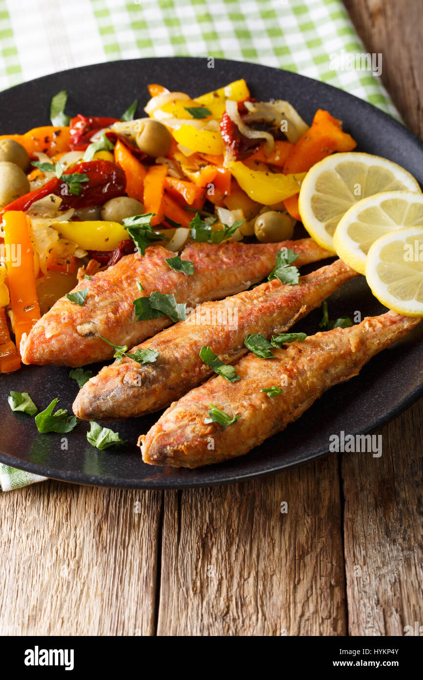Roasted red mullet with stewed vegetables, lemon and greens close-up on ...