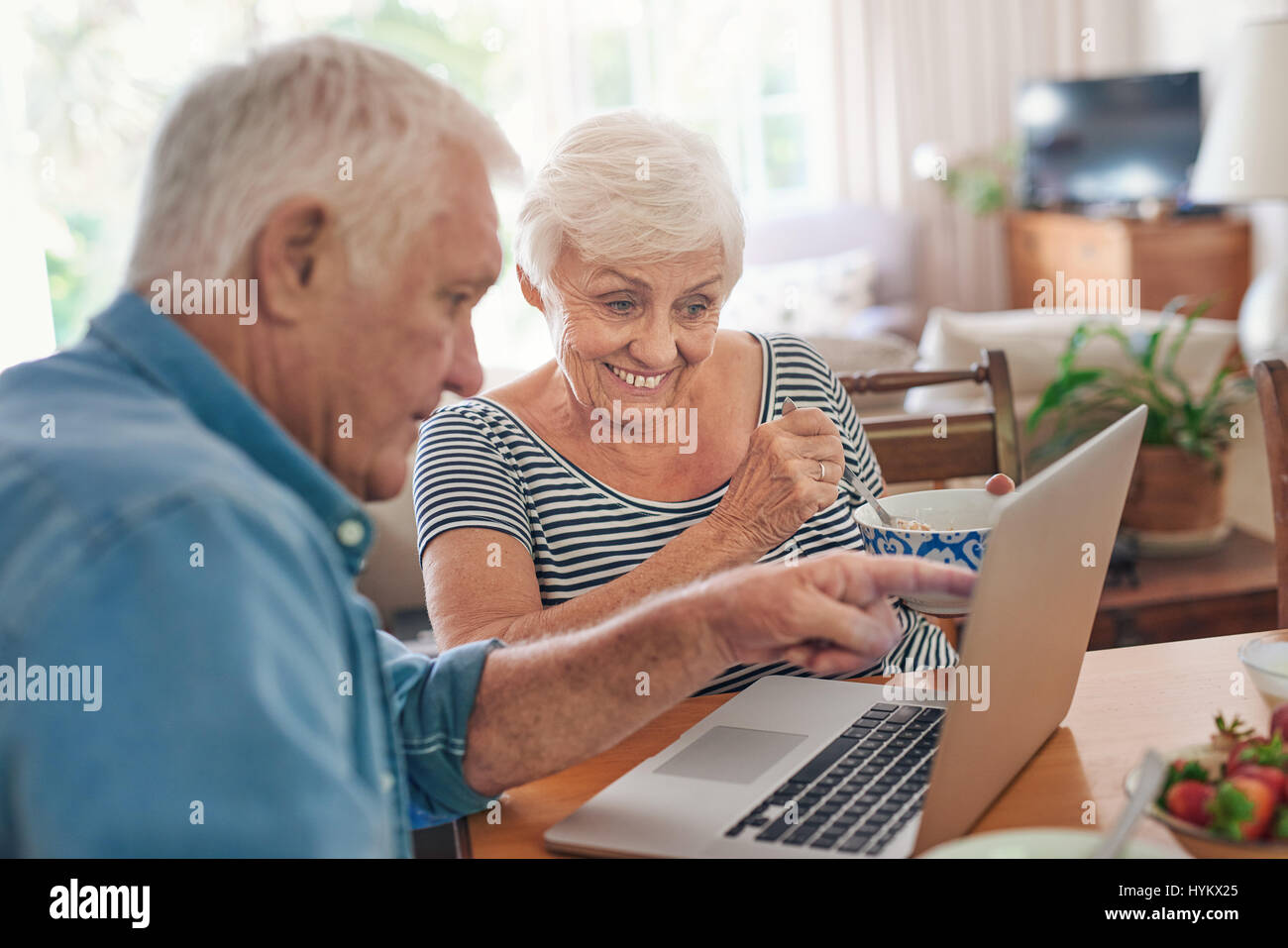 Smiling seniors using a laptop together over breakfast at home Stock ...