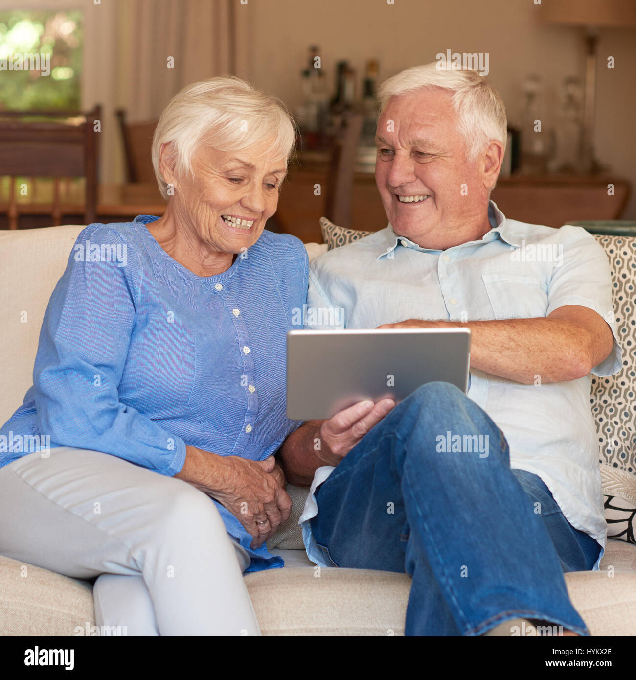 Content seniors using a touchscreen tablet on their couch Stock Photo ...