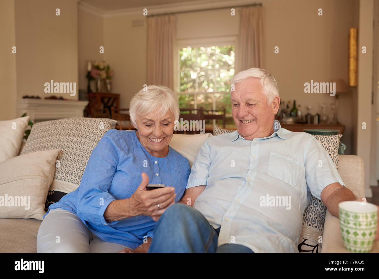 Content seniors reading text messages at home on their sofa Stock Photo ...