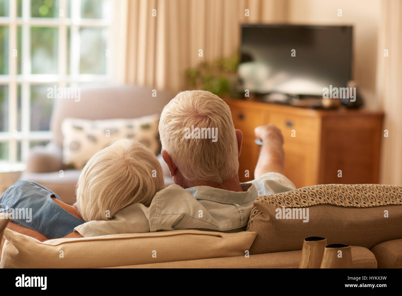 Affectionate senior couple watching television together on their sofa ...
