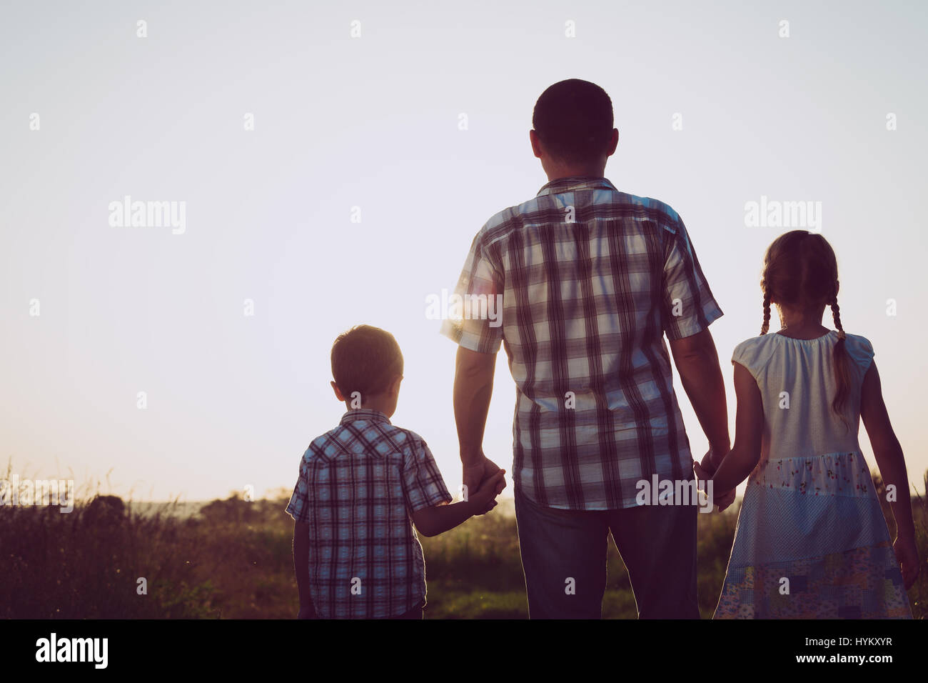 Father and children playing in the park at the sunset time. People ...