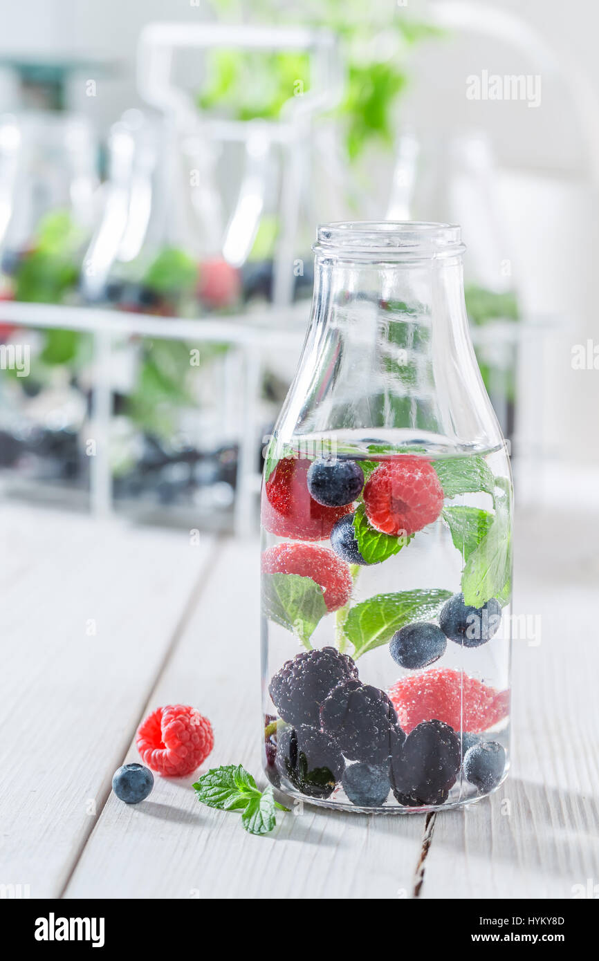 Sparkling water in bottle with raspberries, blueberries and ...