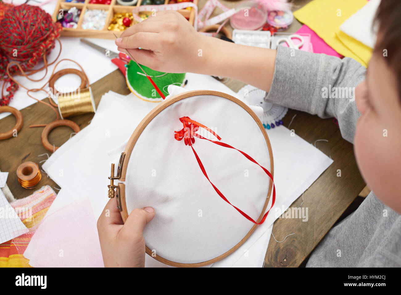 boy embroidered on the hoop, hand closeup and red ribbon on white ...