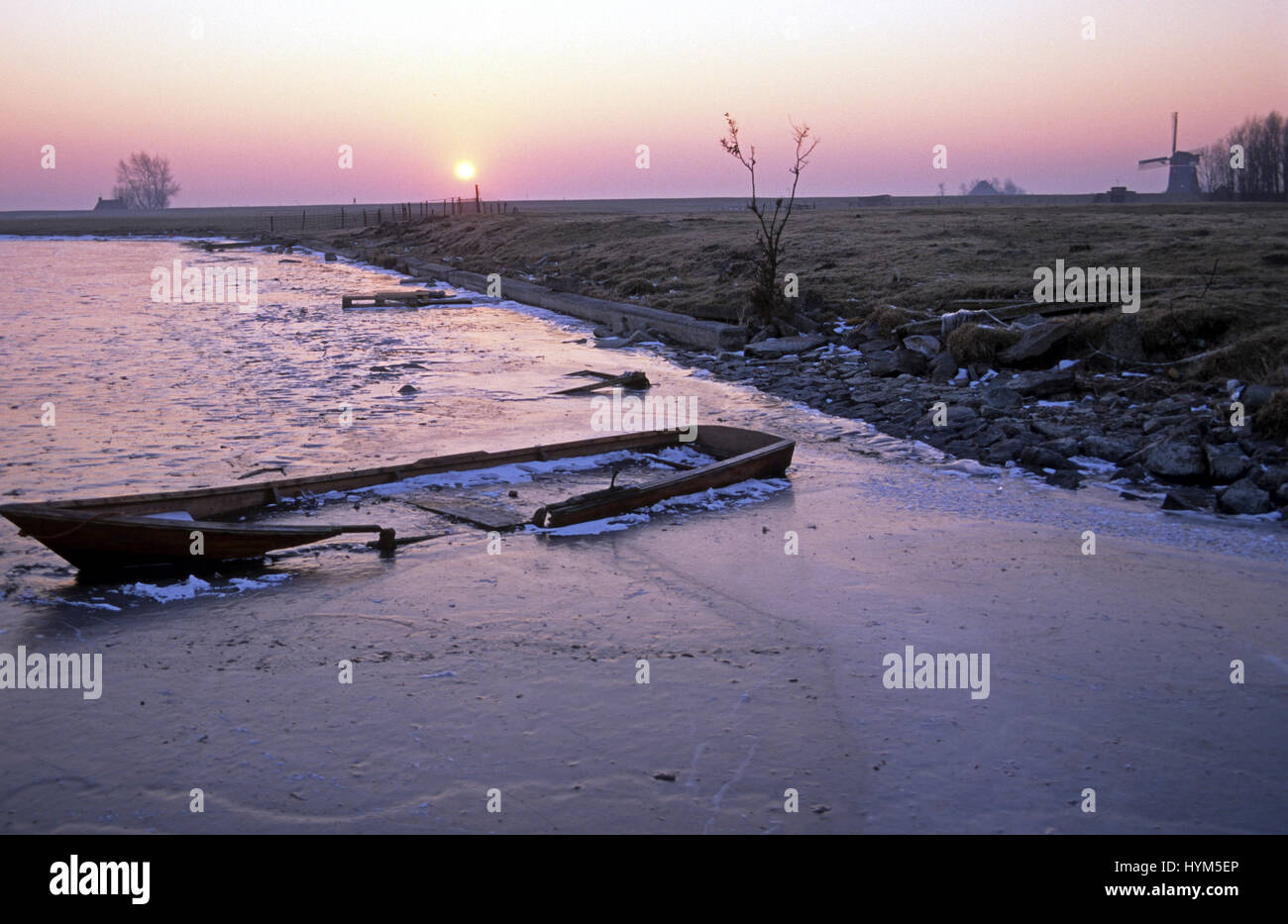 Sinking boat in a frozen lake in the sunset Stock Photo - Alamy