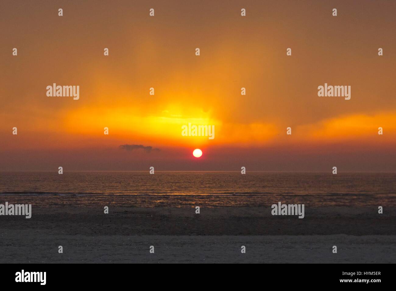 The orange sun setting in the sea Stock Photo - Alamy