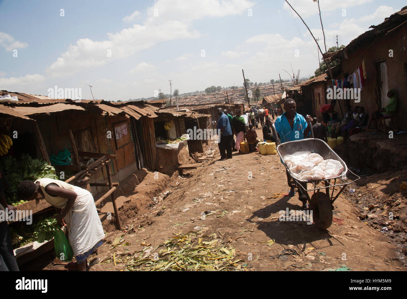 Man pushing a wheel barrow through the market, Kibera slums, Nairobi ...