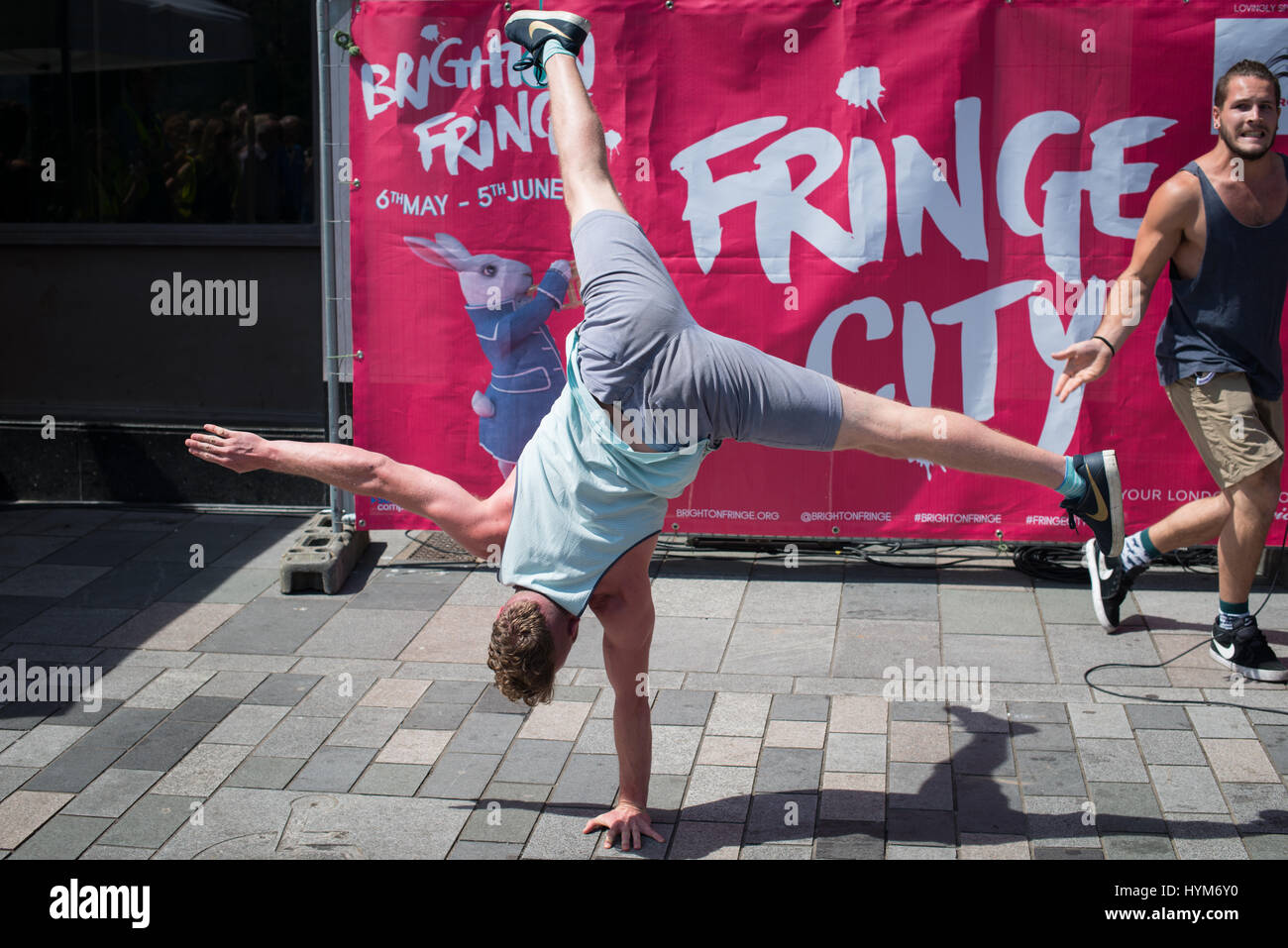 A male acrobat performs a one-handed handstand during a street ...