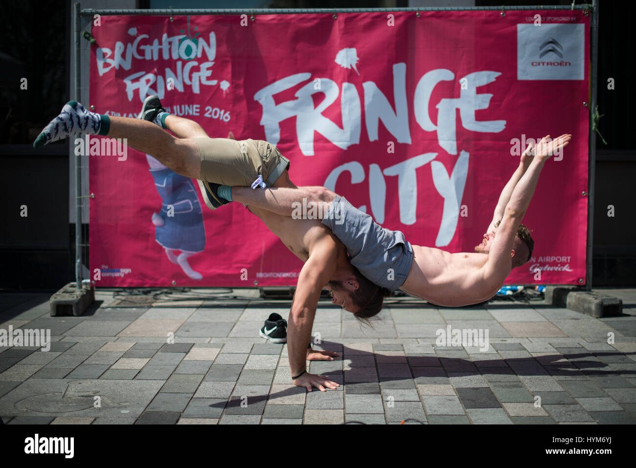 A male acrobat performs a handstand while his friend rests on his back ...