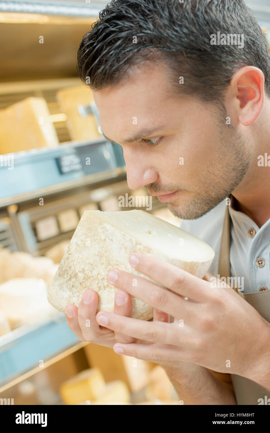 Cheese shop worker smelling on of his cheeses Stock Photo - Alamy