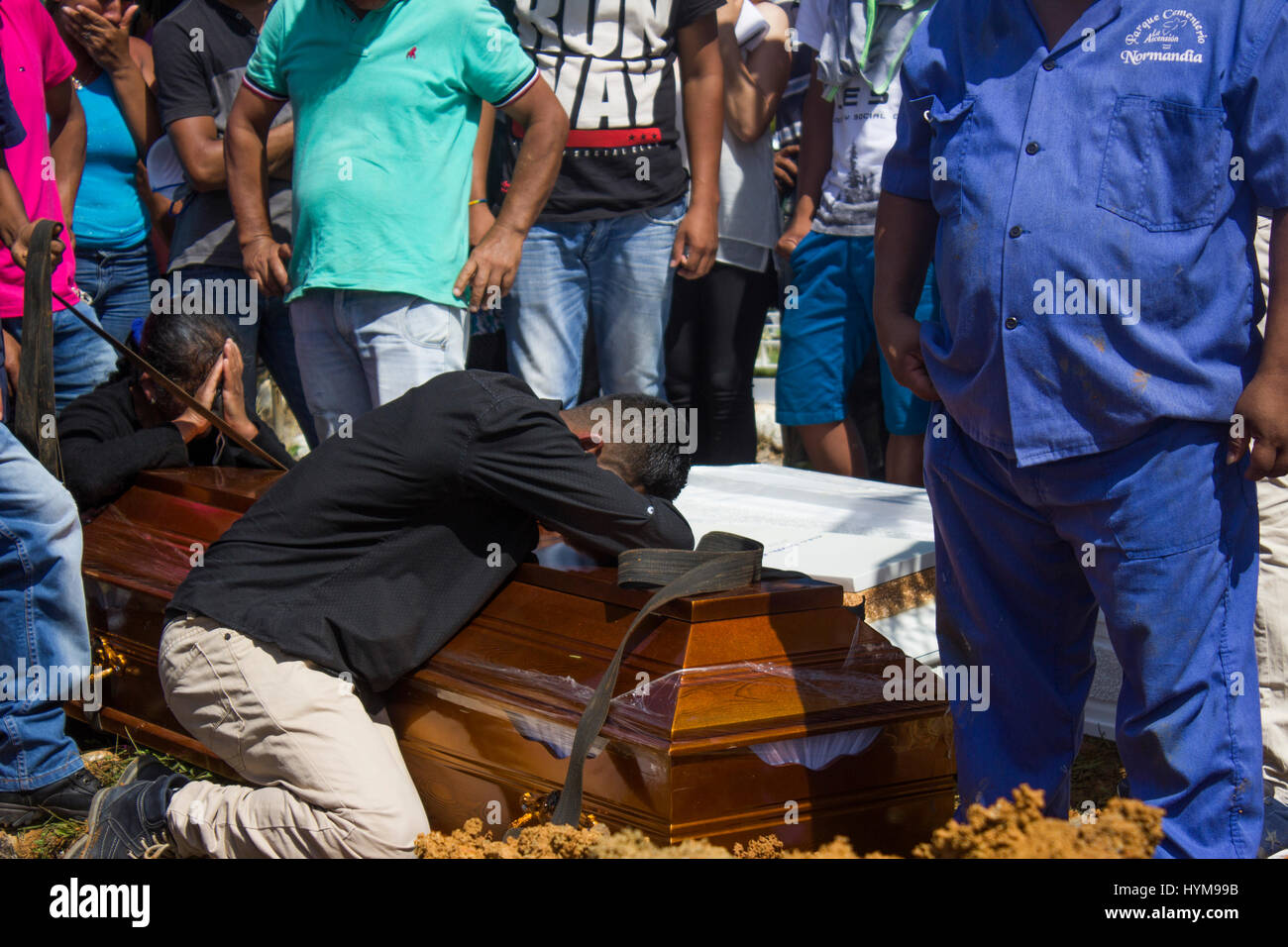 A group of people mourn during a collective burial of the victims of ...