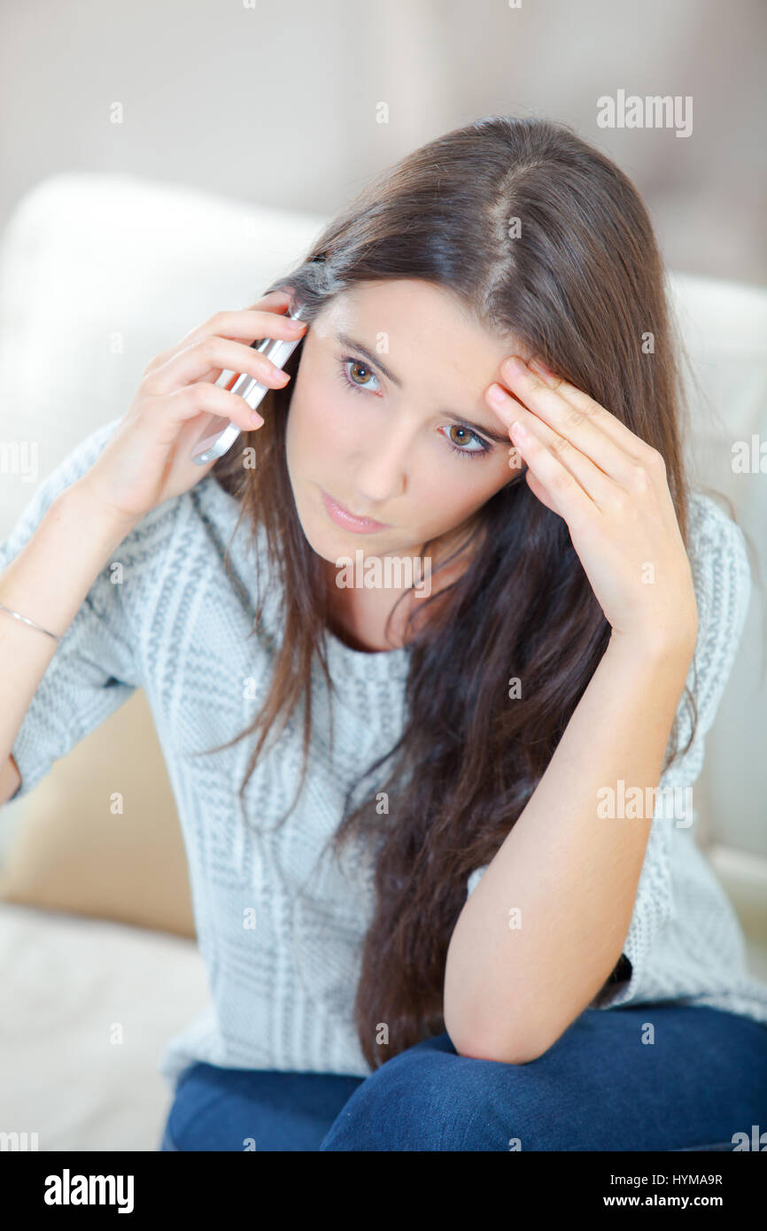 Girl on cellphone holding head in hands Stock Photo - Alamy