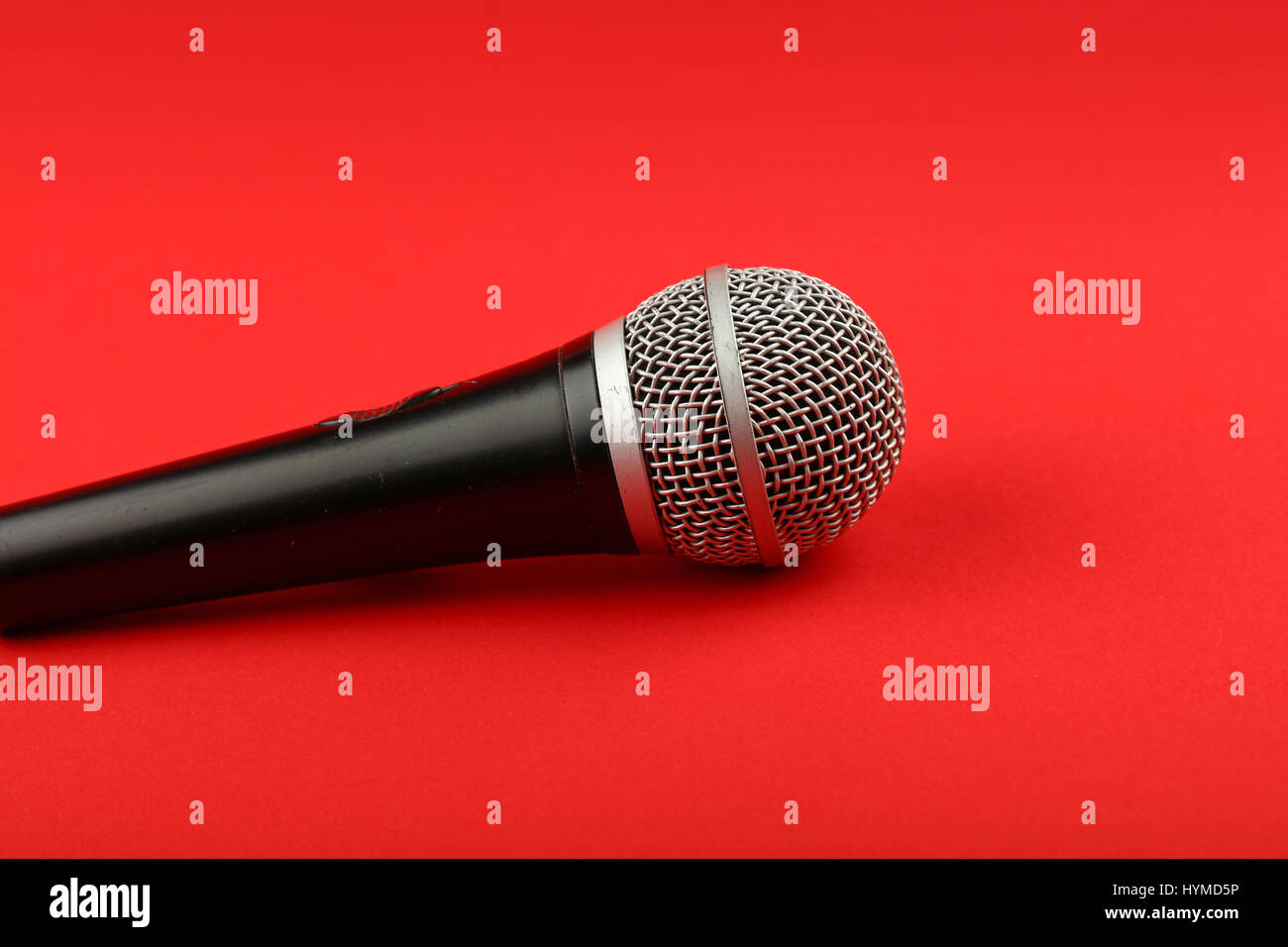 Black and silver vocal microphone side view close up on red background ...