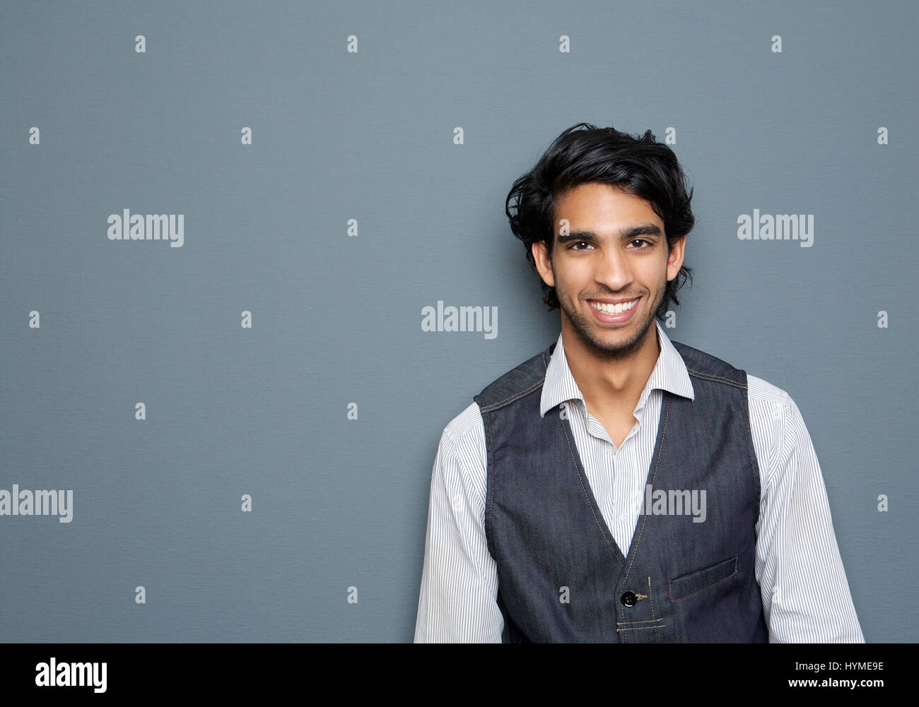 Close up portrait of a handsome young man smiling on gray background ...
