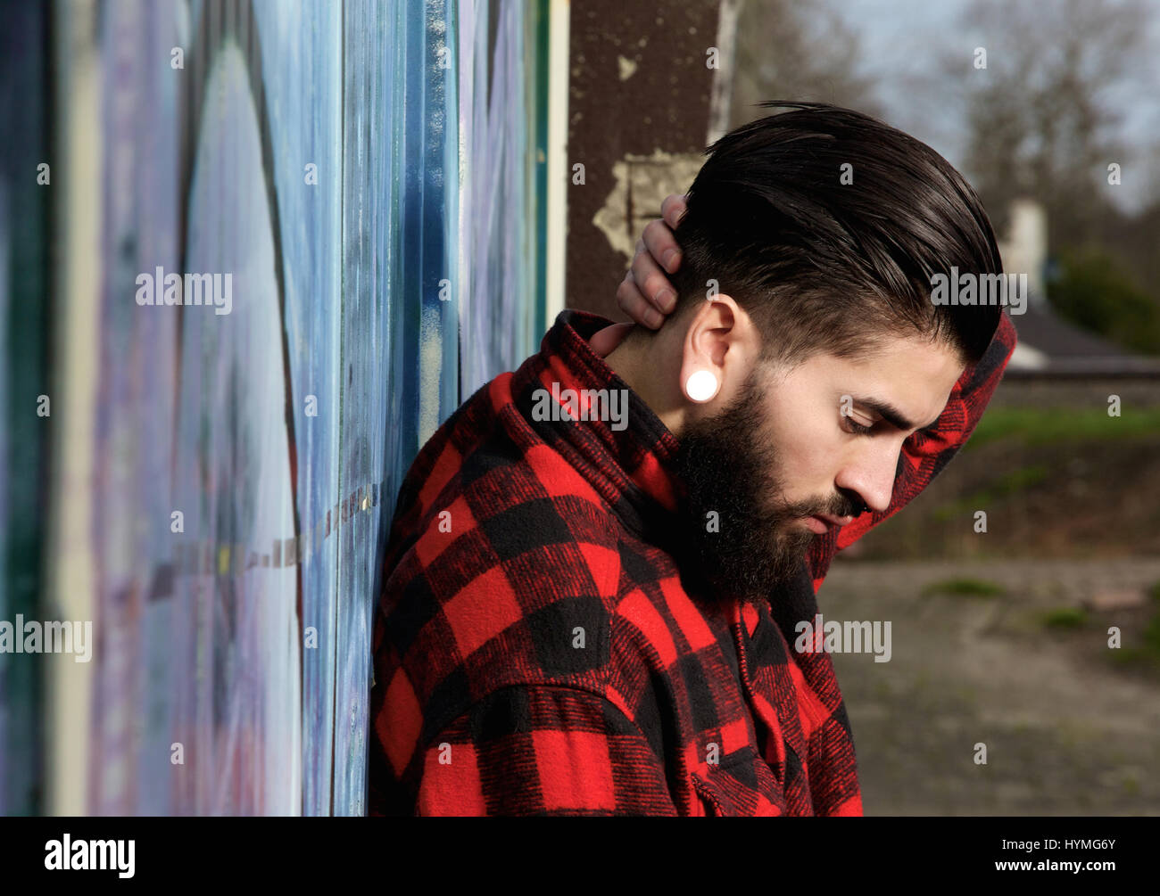 Side view portrait of a young man with beard and piercings outdoors ...