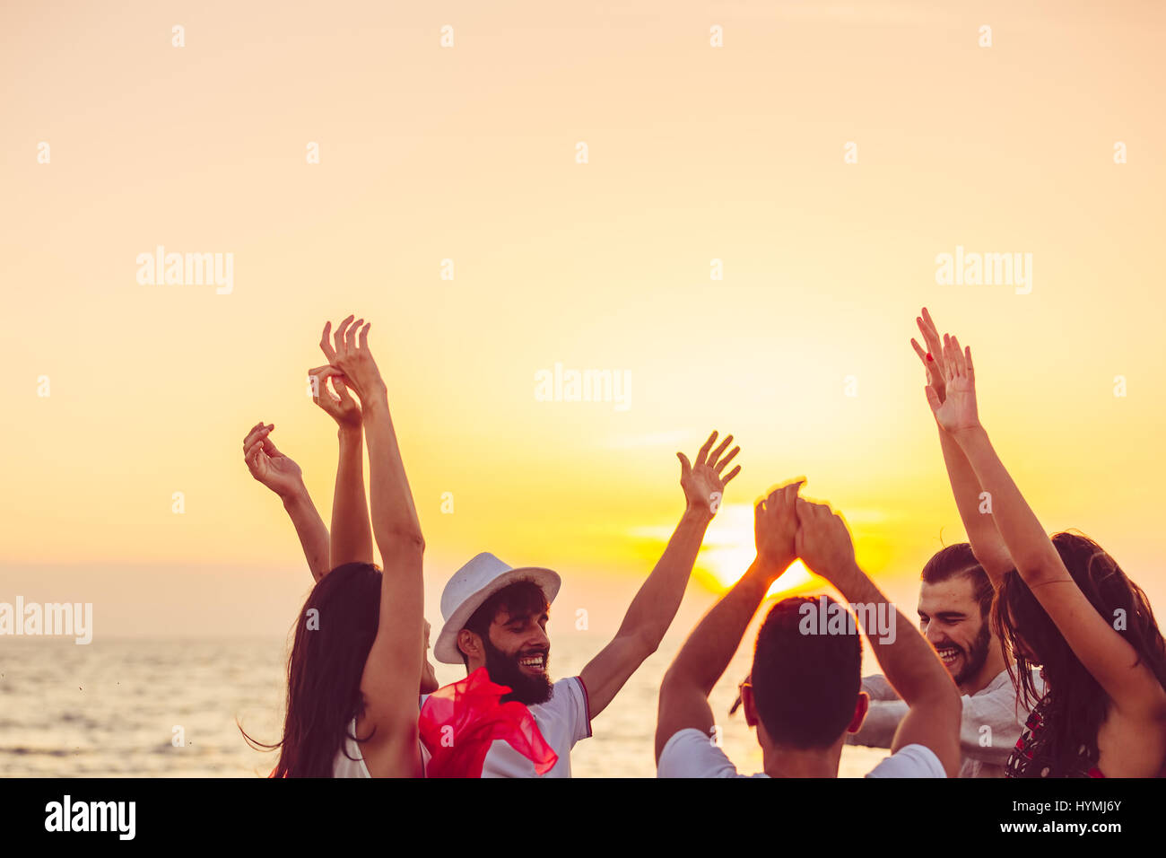 people dancing at the beach with hands up. concept about party, music ...