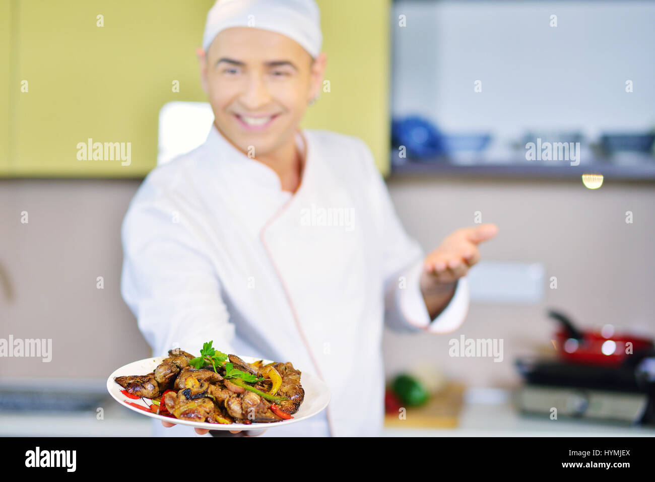 Cook holding plate with food in welcoming gesture Stock Photo - Alamy