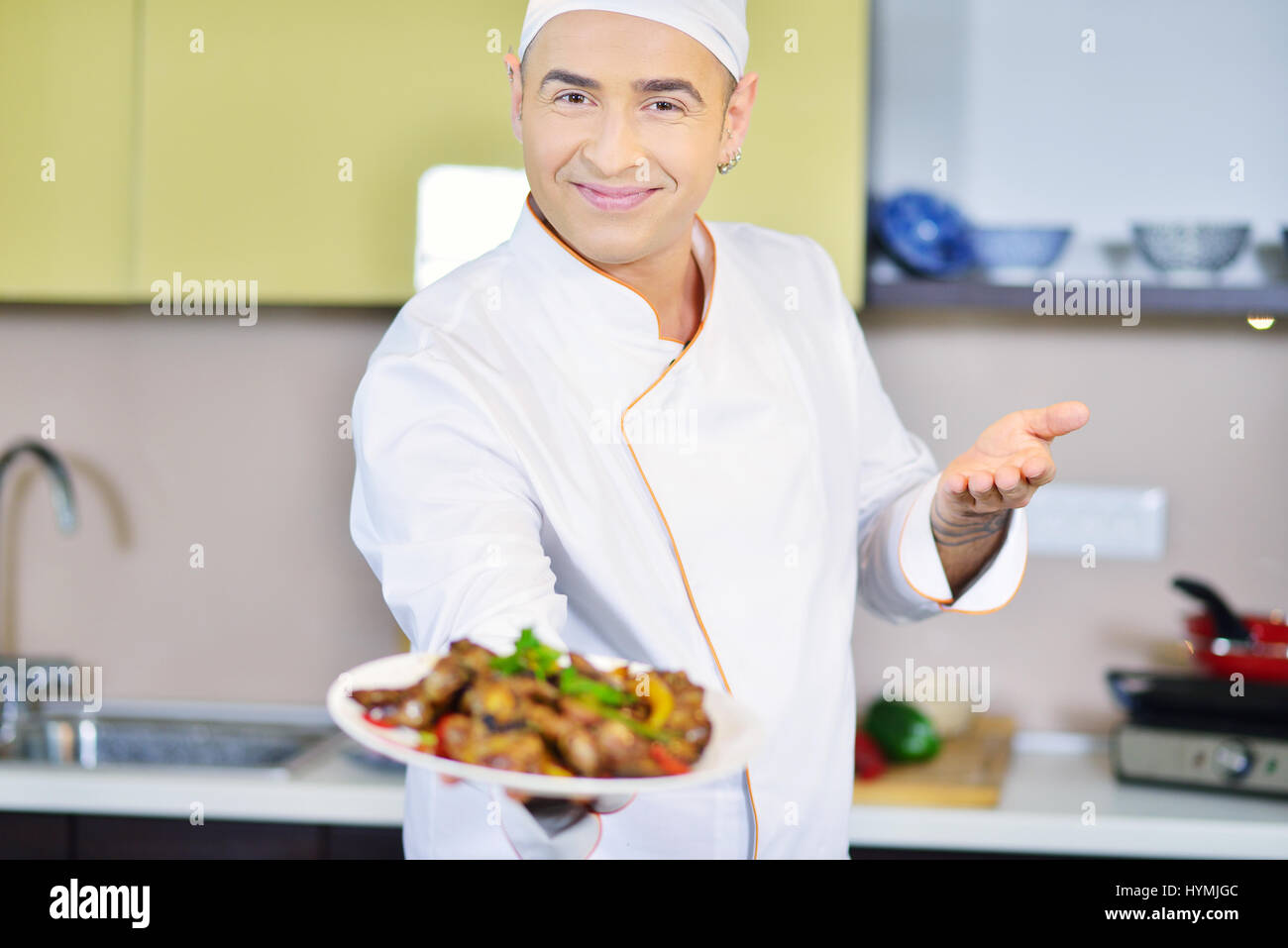 Cook holding plate with food in welcoming gesture Stock Photo - Alamy