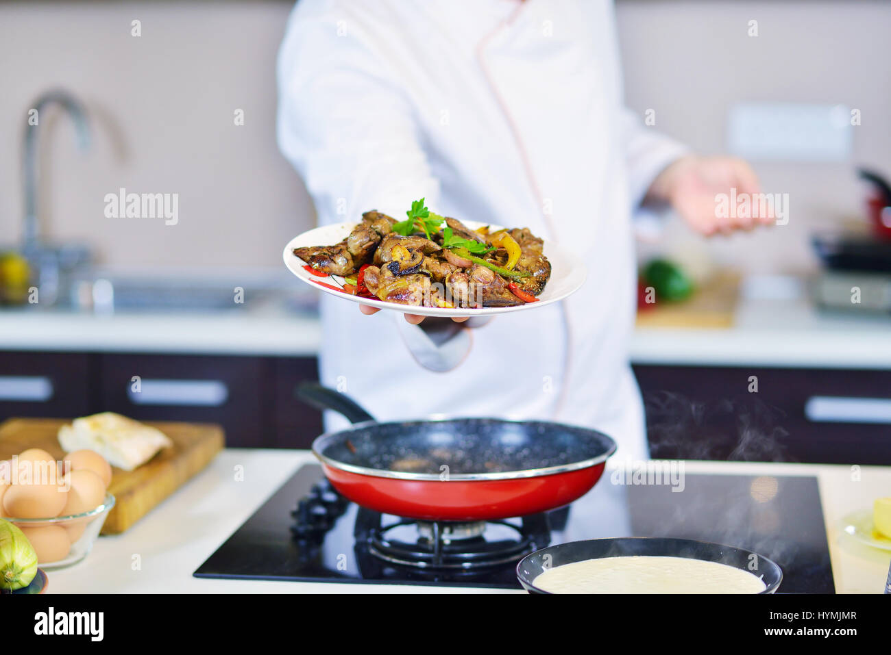 Cook holding plate with food in welcoming gesture Stock Photo - Alamy