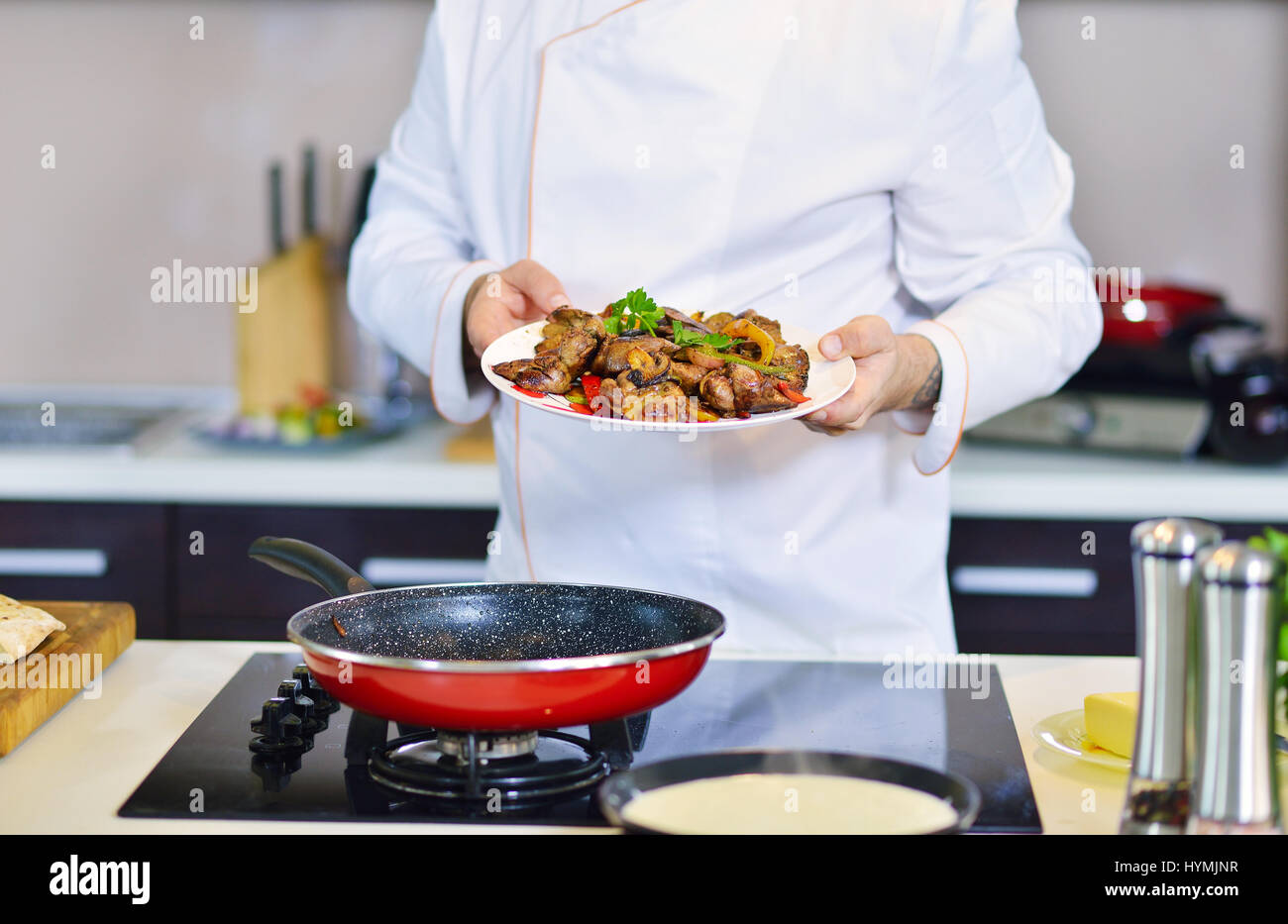 Cook holding plate with food in welcoming gesture Stock Photo - Alamy