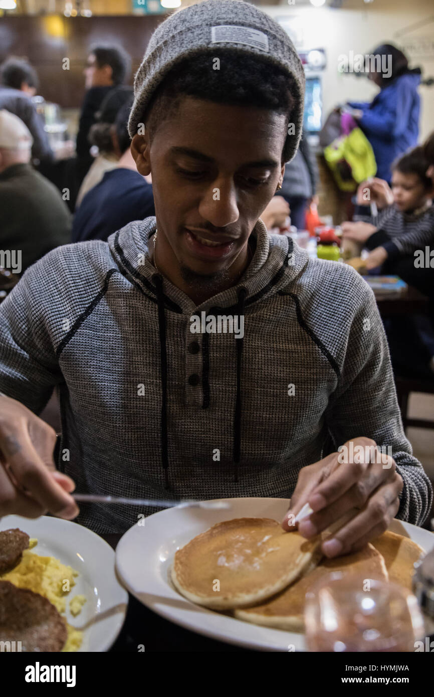 A young, hip man eats brunch at Brooklyn, NYC diner. Shot during the ...