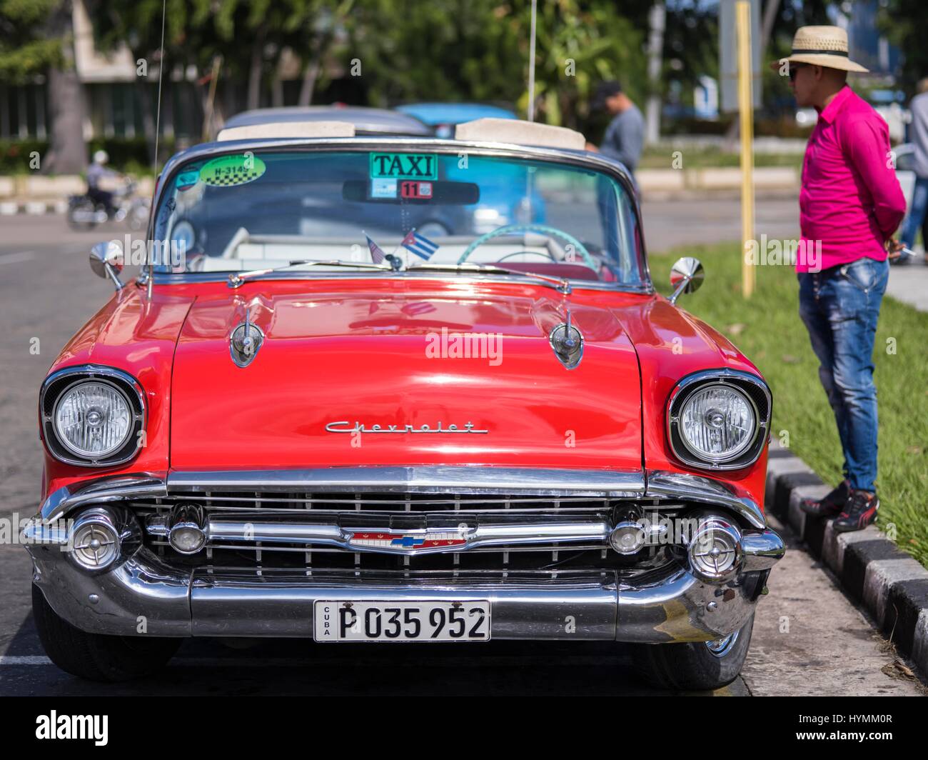 Portrait of a stylish Cuban taxi driver wearing pink shirt standing ...