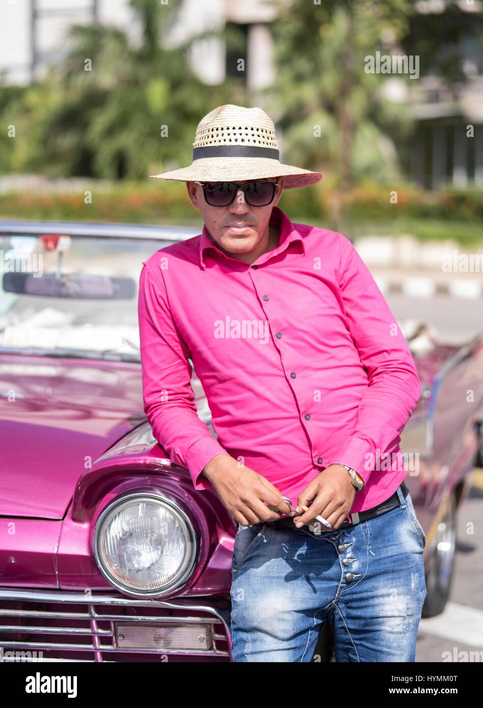 Portrait of a stylish Cuban taxi driver wearing pink shirt standing ...