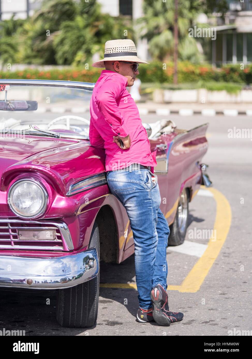 Portrait of a stylish Cuban taxi driver wearing pink shirt standing ...
