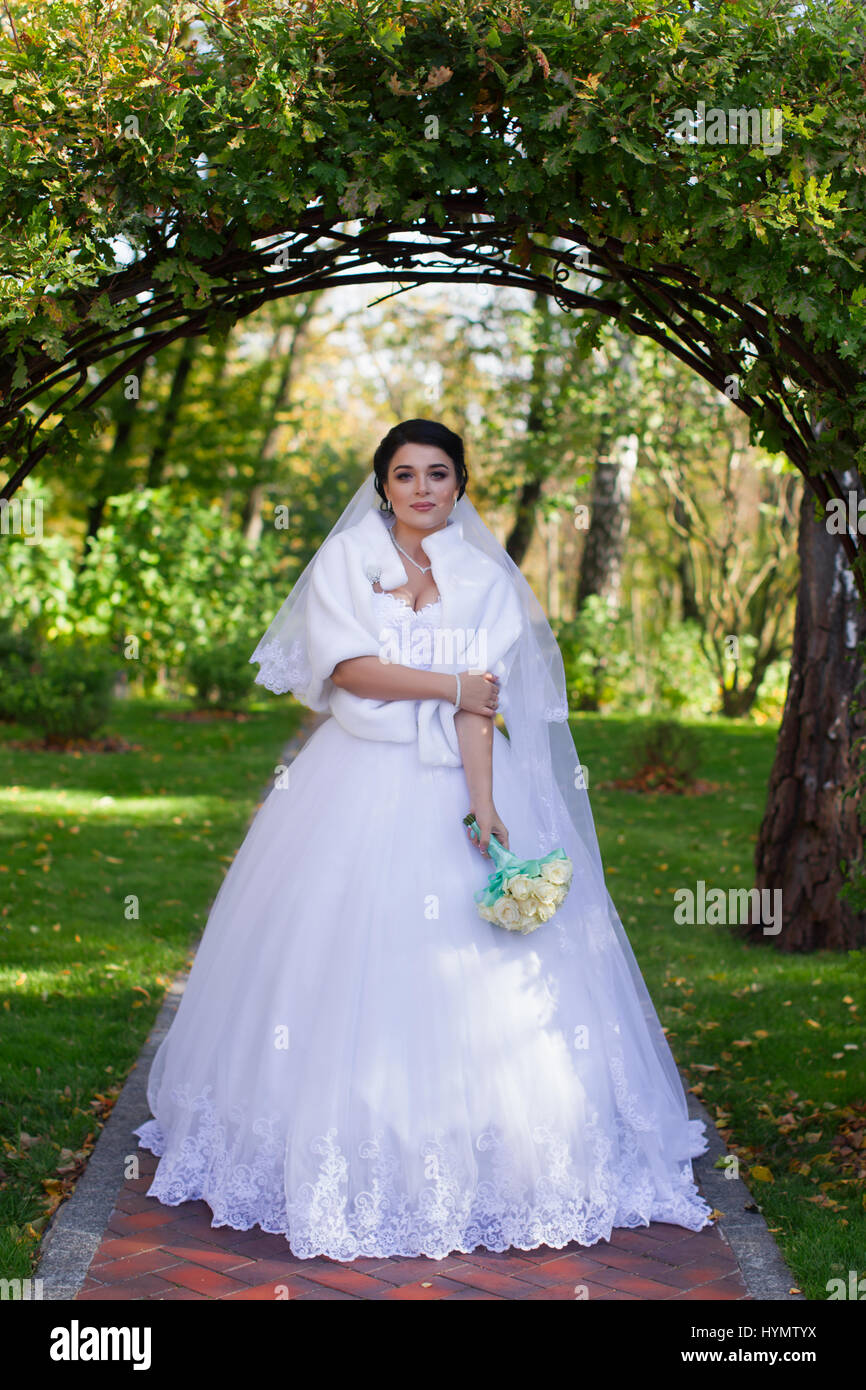 Stylish bride stands under a green arch Stock Photo - Alamy