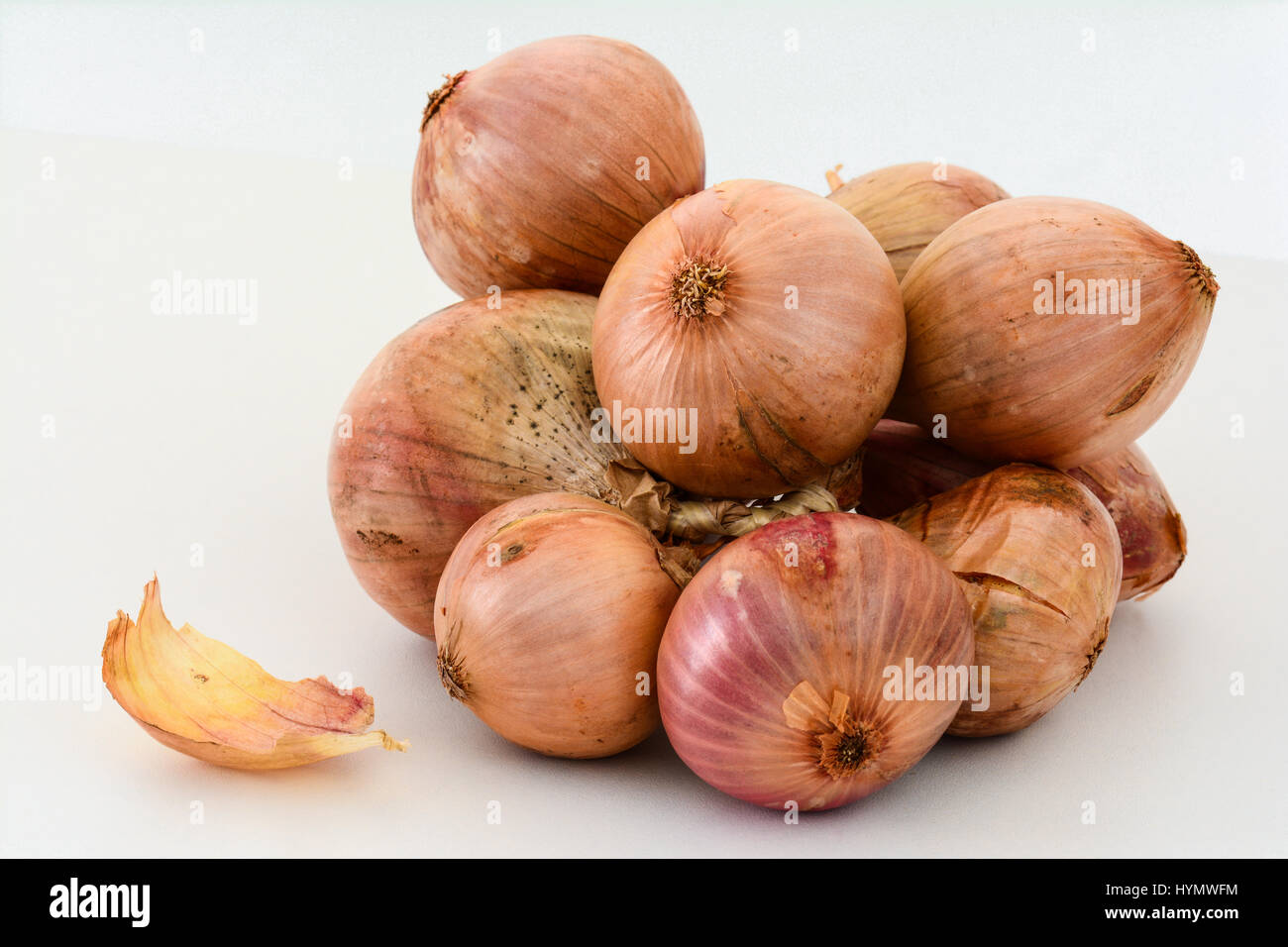 Closeup of a bundle of brown onions on white background Stock Photo - Alamy