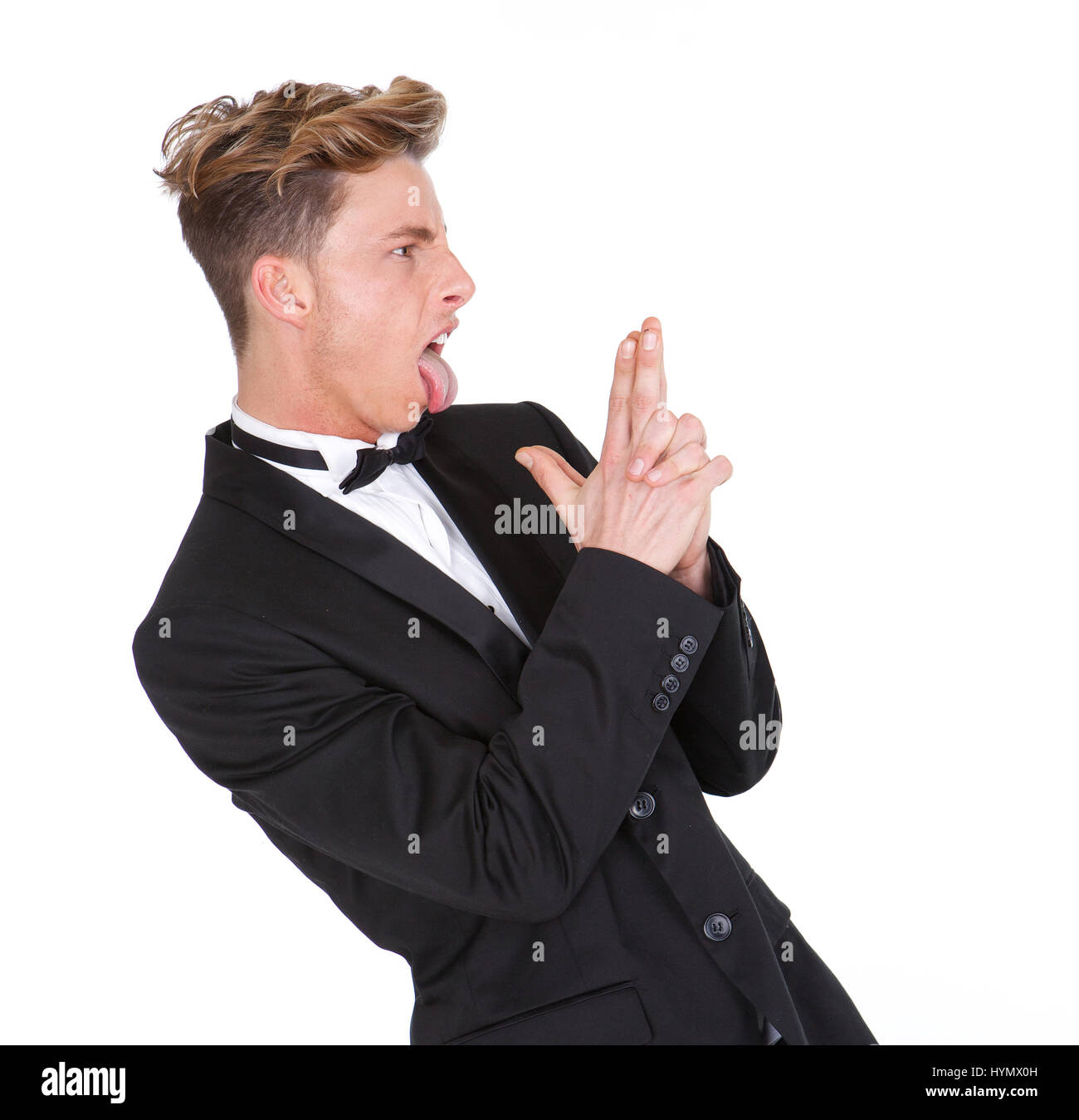 Portrait of a young man in tuxedo shouting with gun hand gesture ...