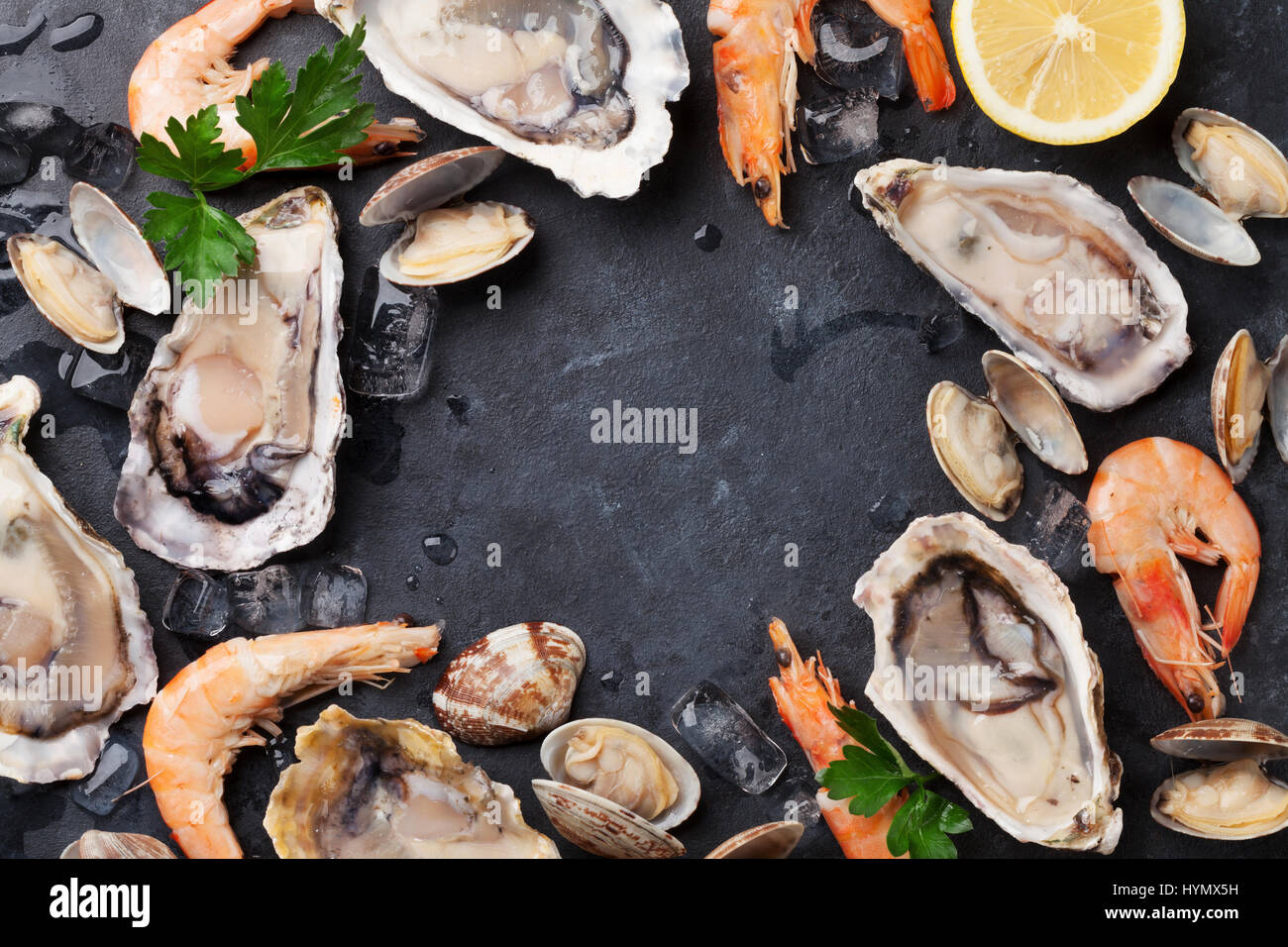 Fresh seafood on stone table. Oysters, prawns and scallops. Top view ...