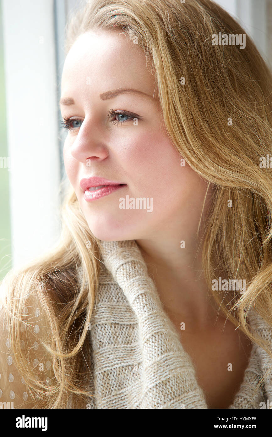 Close up portrait of a beautiful woman staring outside through window ...