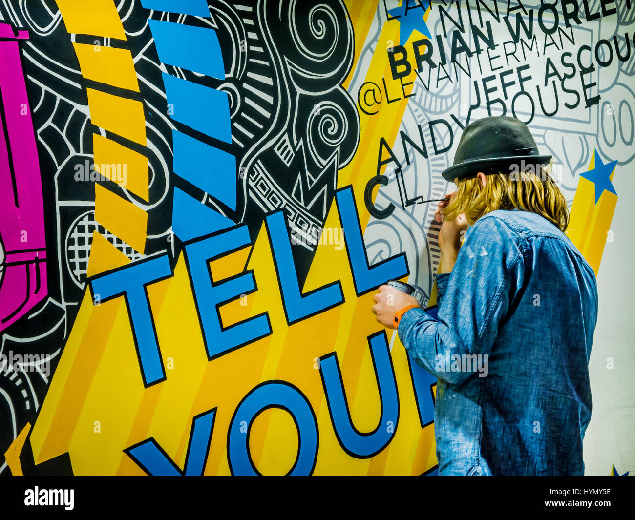Young signboard artist busy painting a signboard using vibrant bright ...