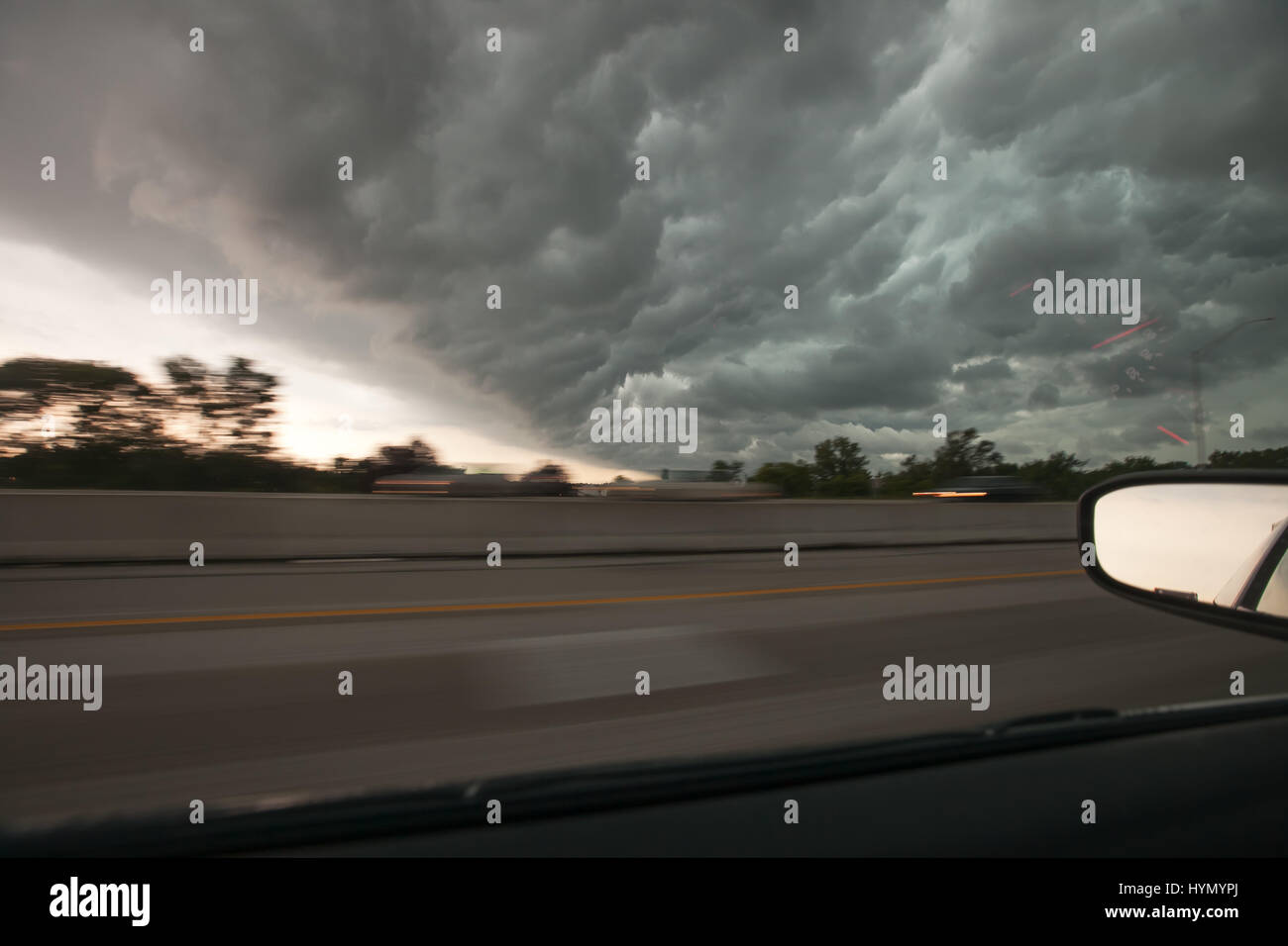 A view of dark storm clouds from a speeding car on an open roadway ...