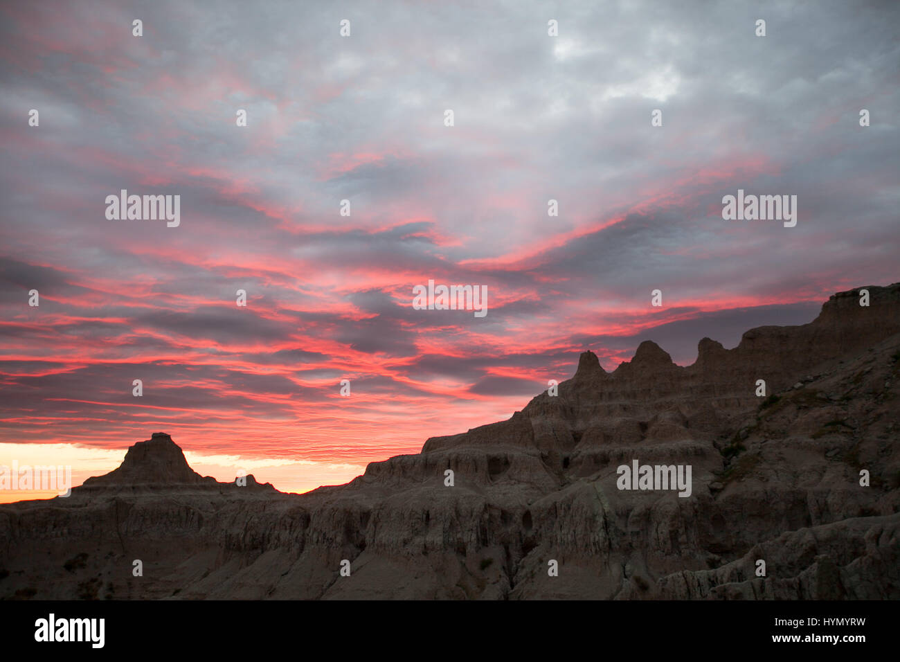 A colorful sunrise appears behind buttes at Badlands National Park ...