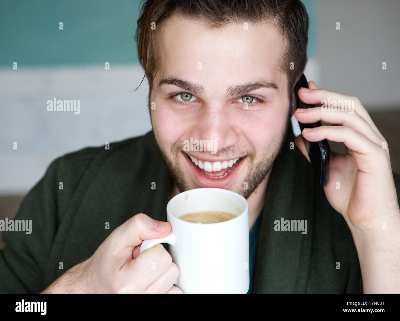 Close up portrait of a handsome young man drinking coffee and calling ...