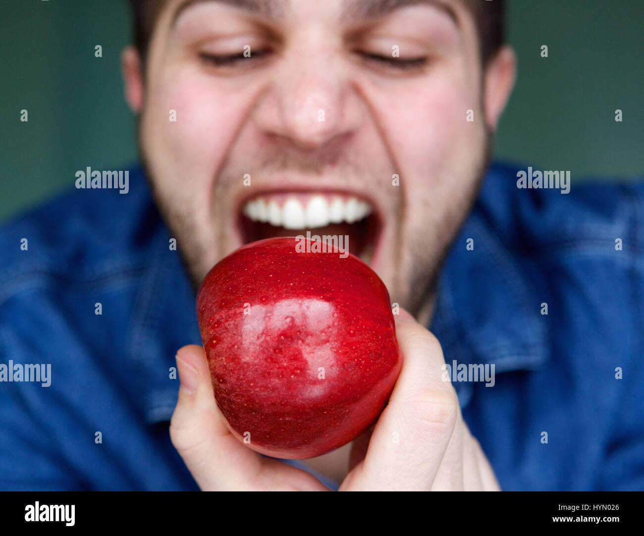 Close up portrait of a young man eating red apple Stock Photo - Alamy